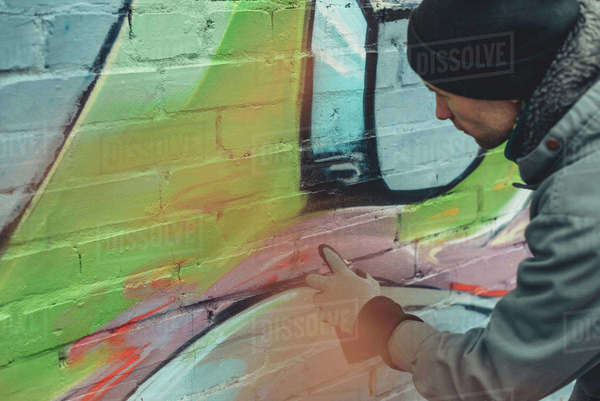 Man painting colorful graffiti on wall - Stock Photo - Dissolve