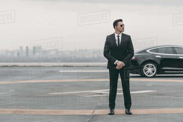 Serious bodyguard standing with sunglasses and security earpiece on ...