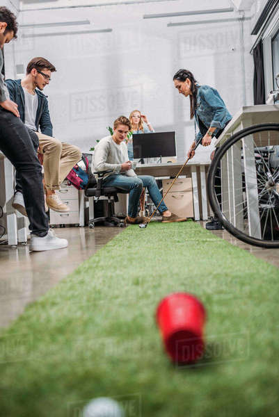 Cheerful colleagues playing in mini golf at modern office - Stock Photo ...