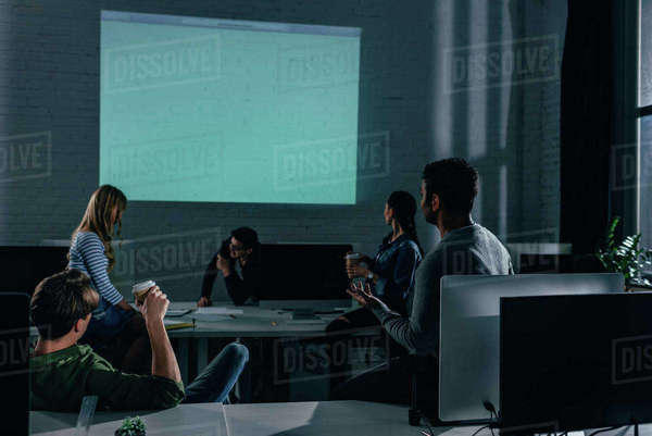 People watching presentation in office at nighttime. blank screen ...