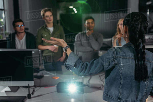 Young people watching presentation in modern office, woman pointing on ...
