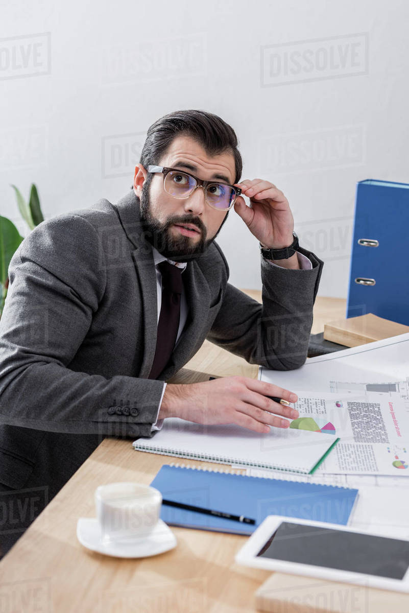 Businessman sitting at table and looking up - Royalty-free Stock Photo ...