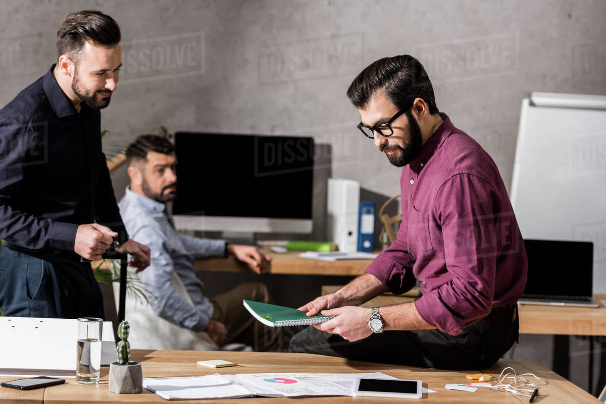 Businessman sitting on working table and holding documents - Royalty ...