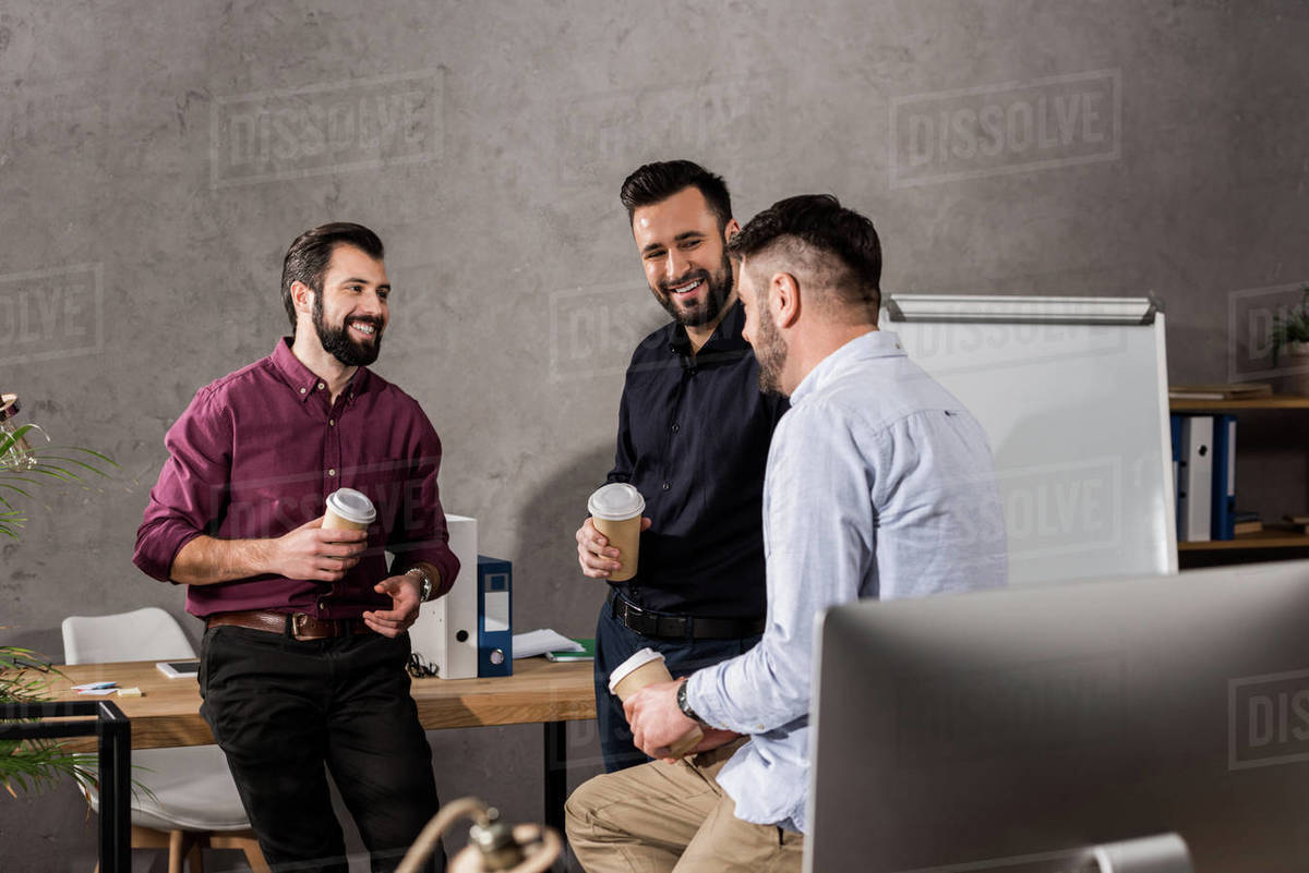 Smiling businessmen talking during coffee break at office - Royalty ...