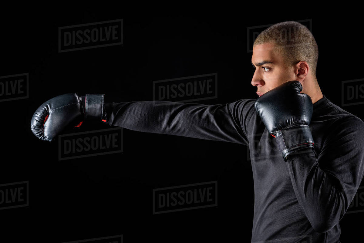 side view of african american boxer making hit isolated on black ...