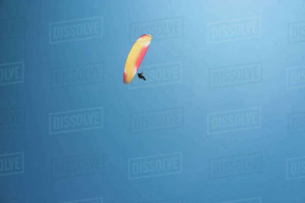 man flying on paraglider, blue sky on background - Stock Photo - Dissolve