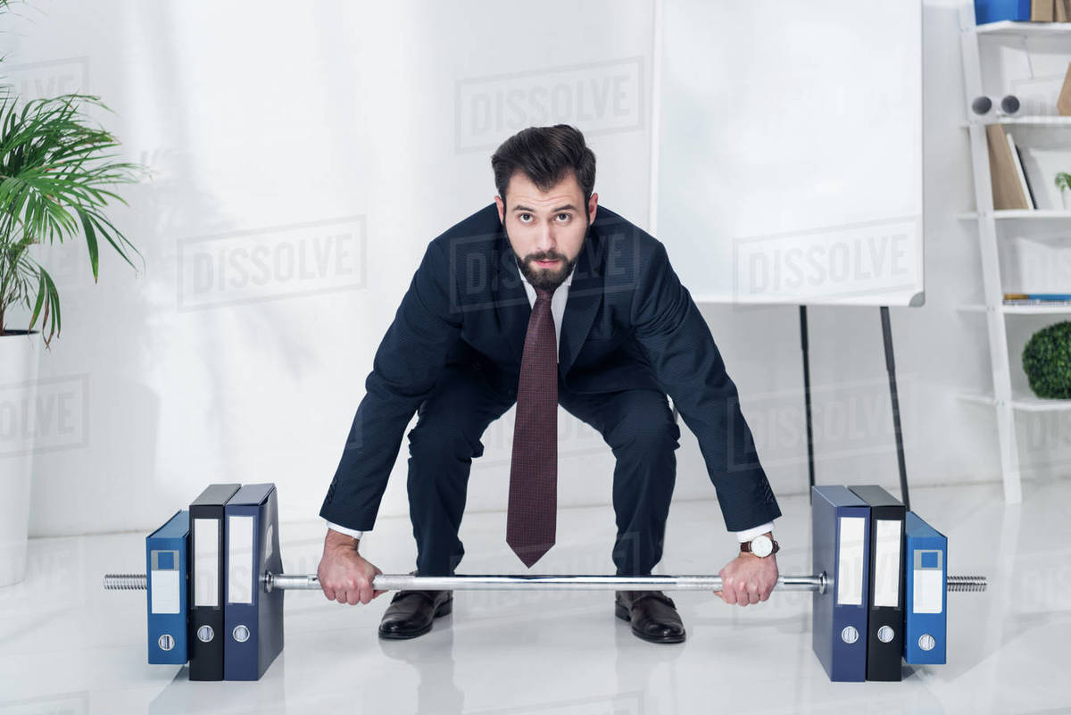 Businessman in suit weightlifting folders in office - Royalty-free ...