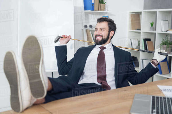 Smiling businessman with golf equipment at workplace in office ...
