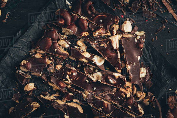 Top view of dark chocolate with nuts pieces on crumpled wrapper ...