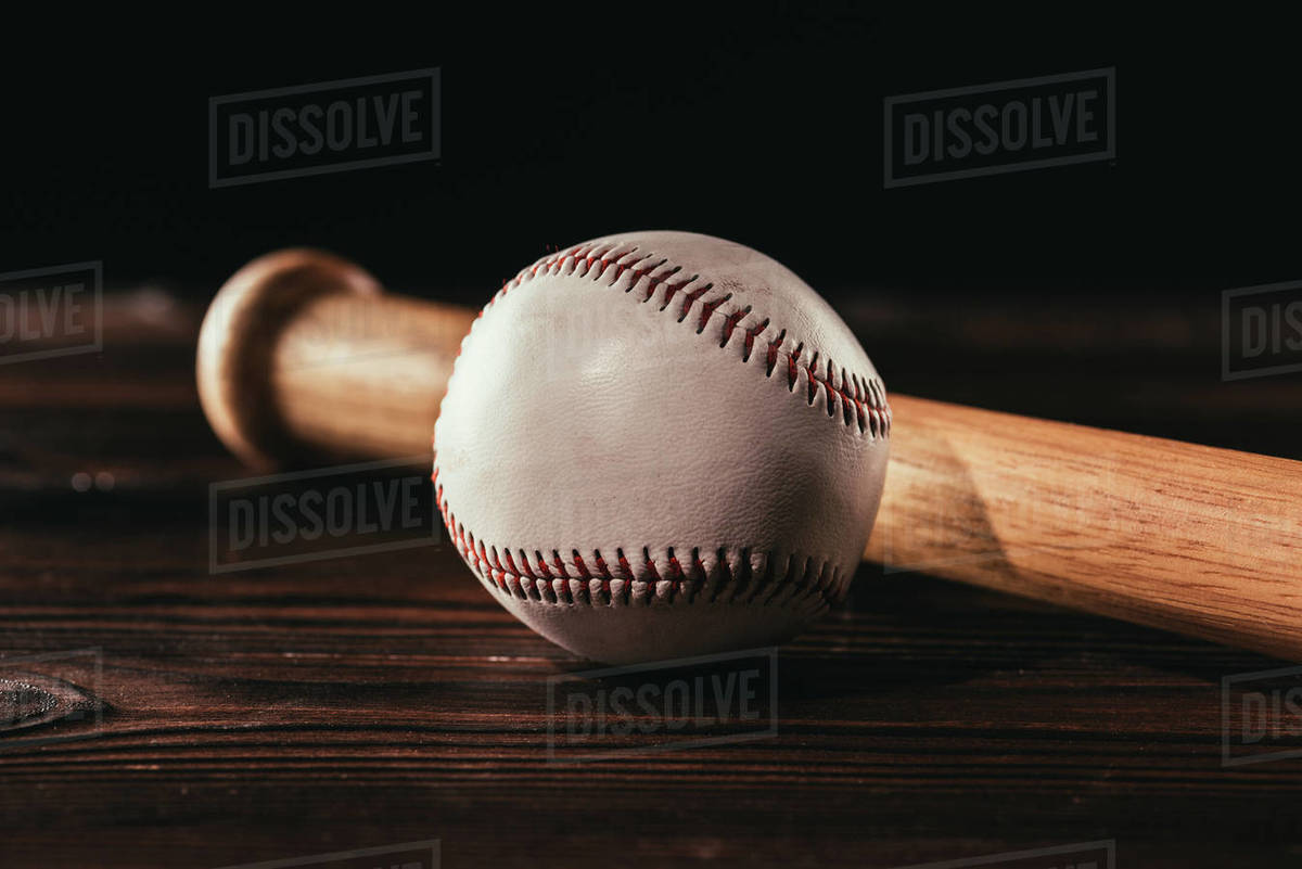Close-up view of white leather baseball ball and bat on wooden table ...