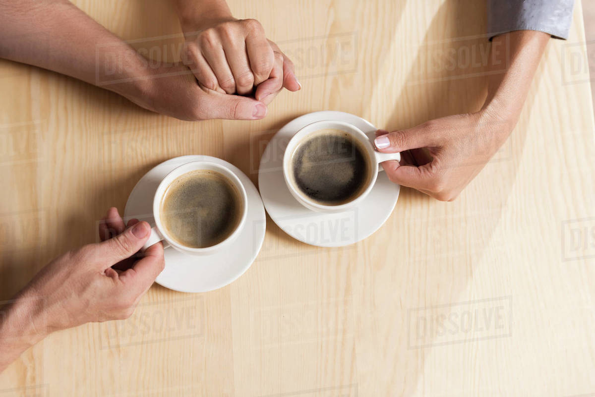 Top view of couple holding by hands and drinking coffee - Royalty-free ...