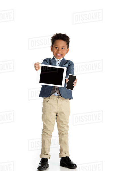 Smiling african american kid showing tablet and smartphone on white ...