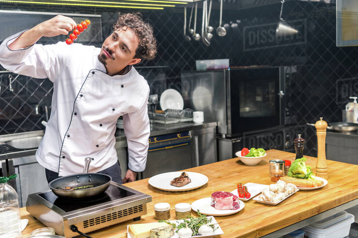 Happy chef looking at cherry tomatoes - Royalty-free Stock Photo | Dissolve