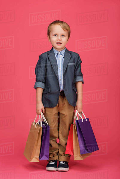 cute little boy with shopping bags in hands isolated on pink - Royalty ...
