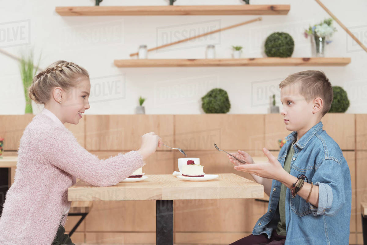 children sitting at table at cafe while looking at each other - Stock ...