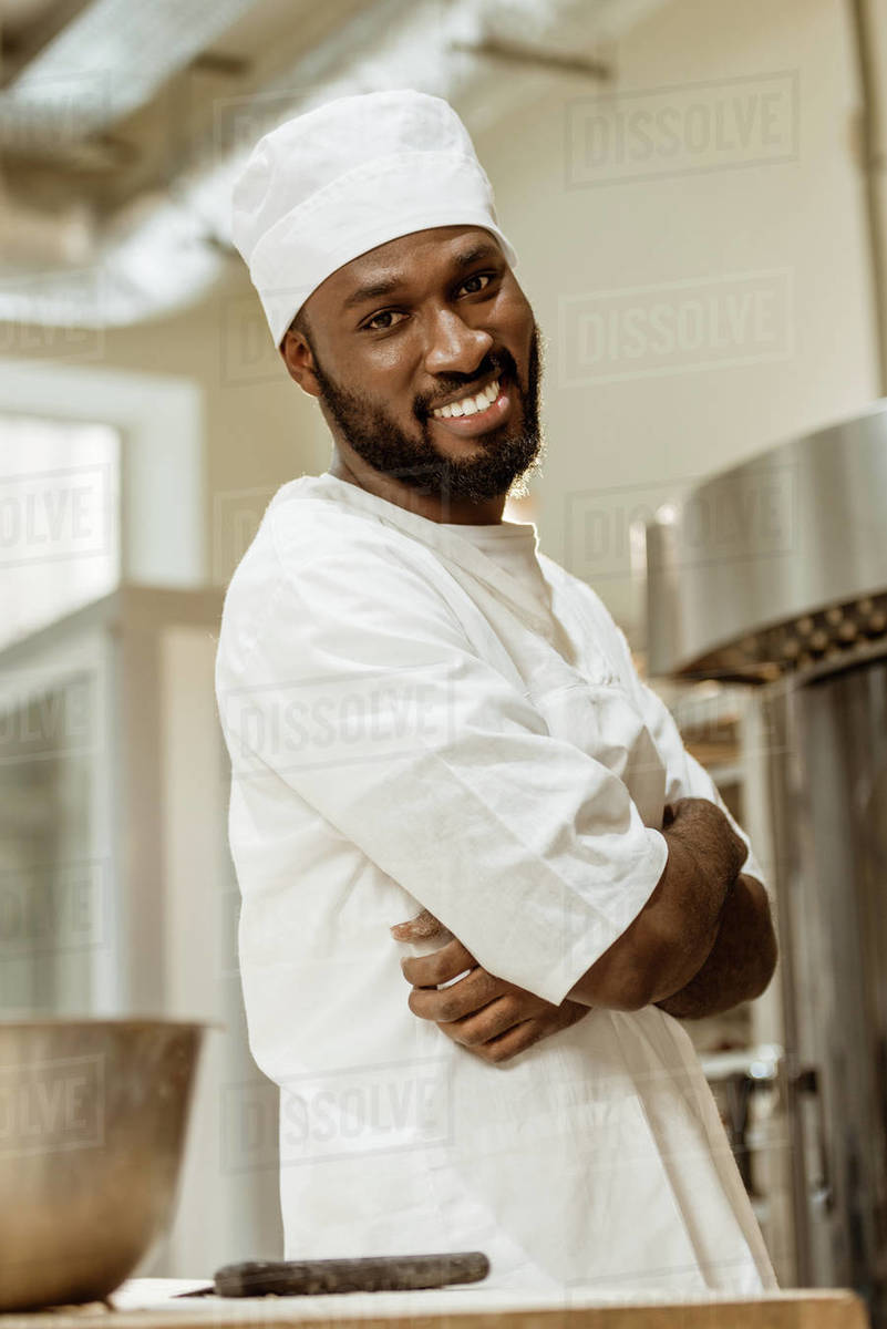 Handsome african american baker with crossed hands looking at camera on ...