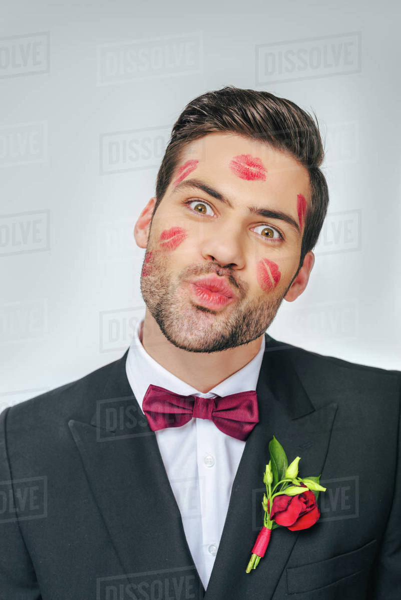 Portrait of handsome groom in suit with red lipstick on face isolated ...