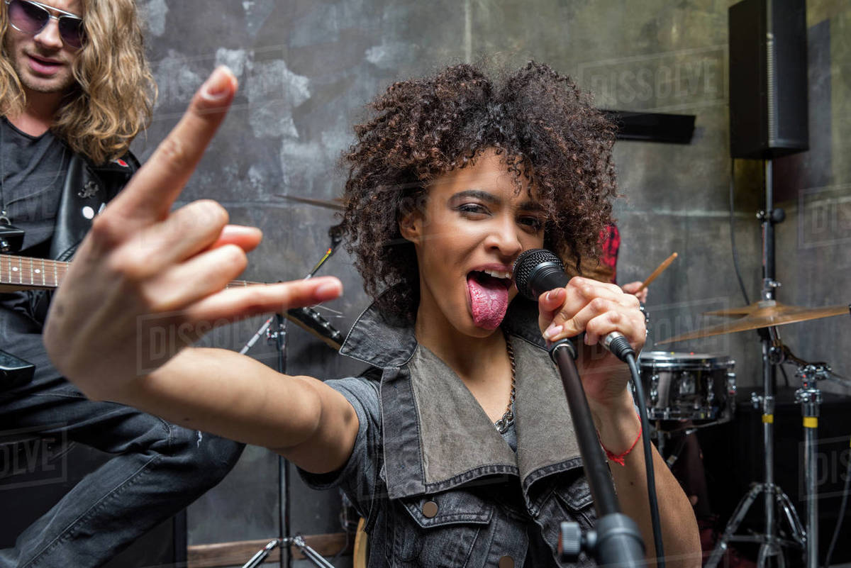 Woman with microphone showing rock sign in studio, rock and roll girl ...
