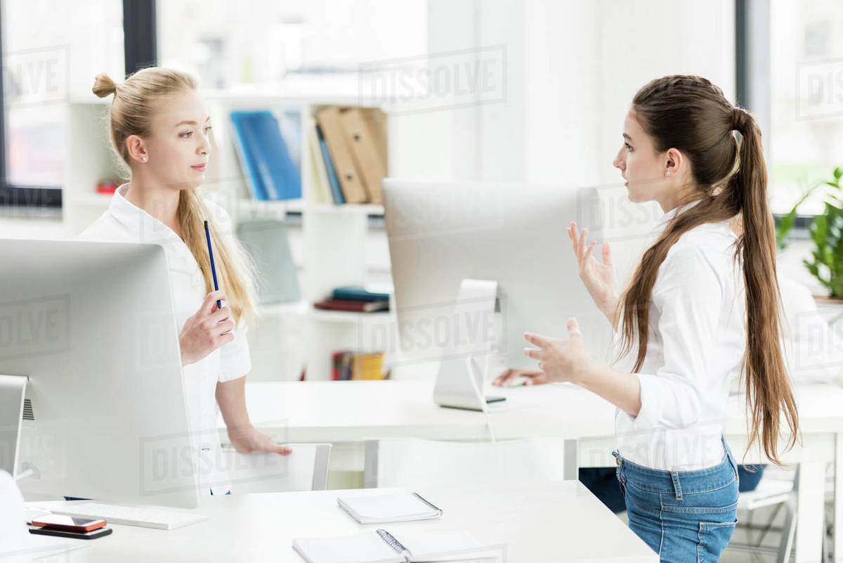 Side view of teen girls discussing task together while standing in ...