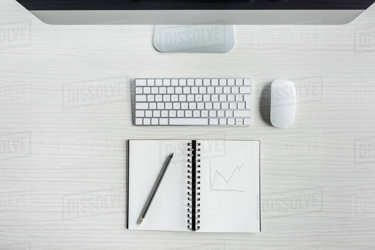 Top view of computer screen, mouse, keyboard and notebook with drawn ...