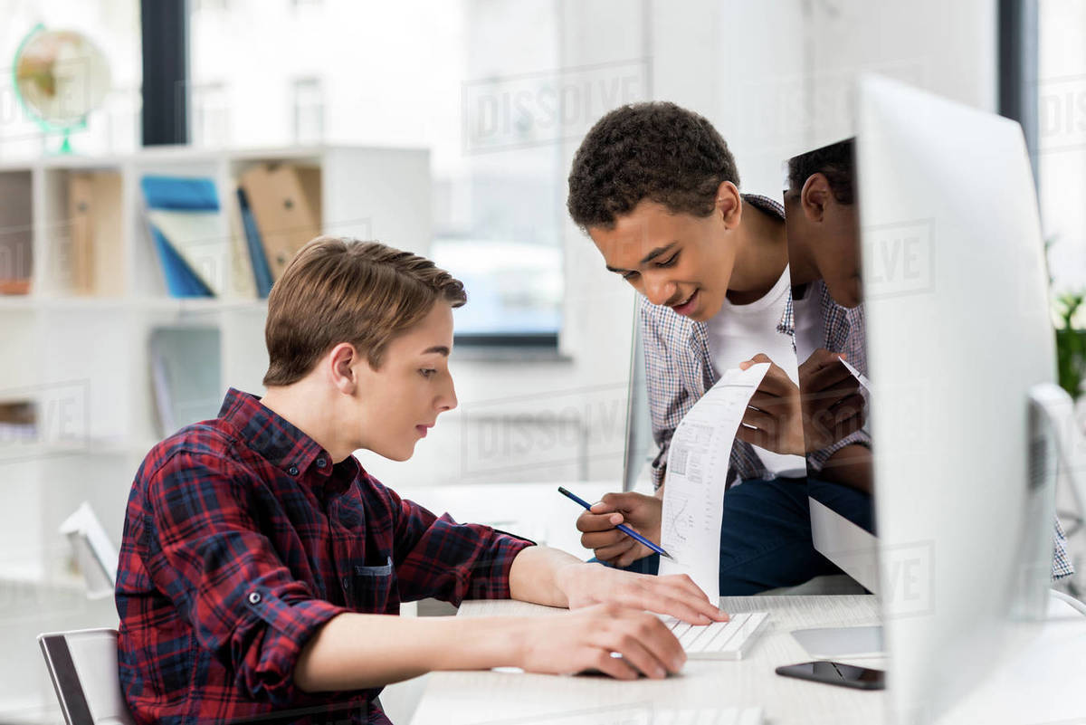 Side view of multicultural teen boys studying together in class ...