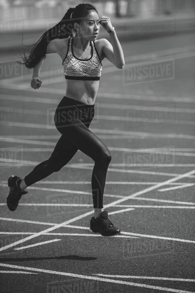 Athletic young sportswoman sprinting on running track stadium, black ...