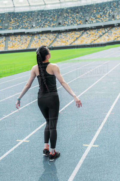 Back view of young fitness woman in sportswear standing on running ...