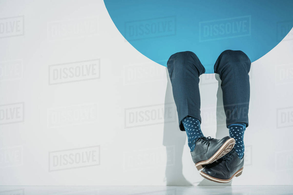 Close-up partial view of stylish man falling into hole on grey ...