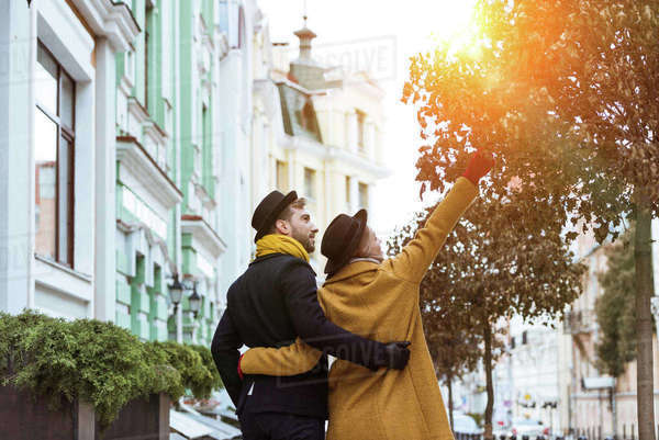 Back view of young couple hugging and walking at street - Royalty-free ...