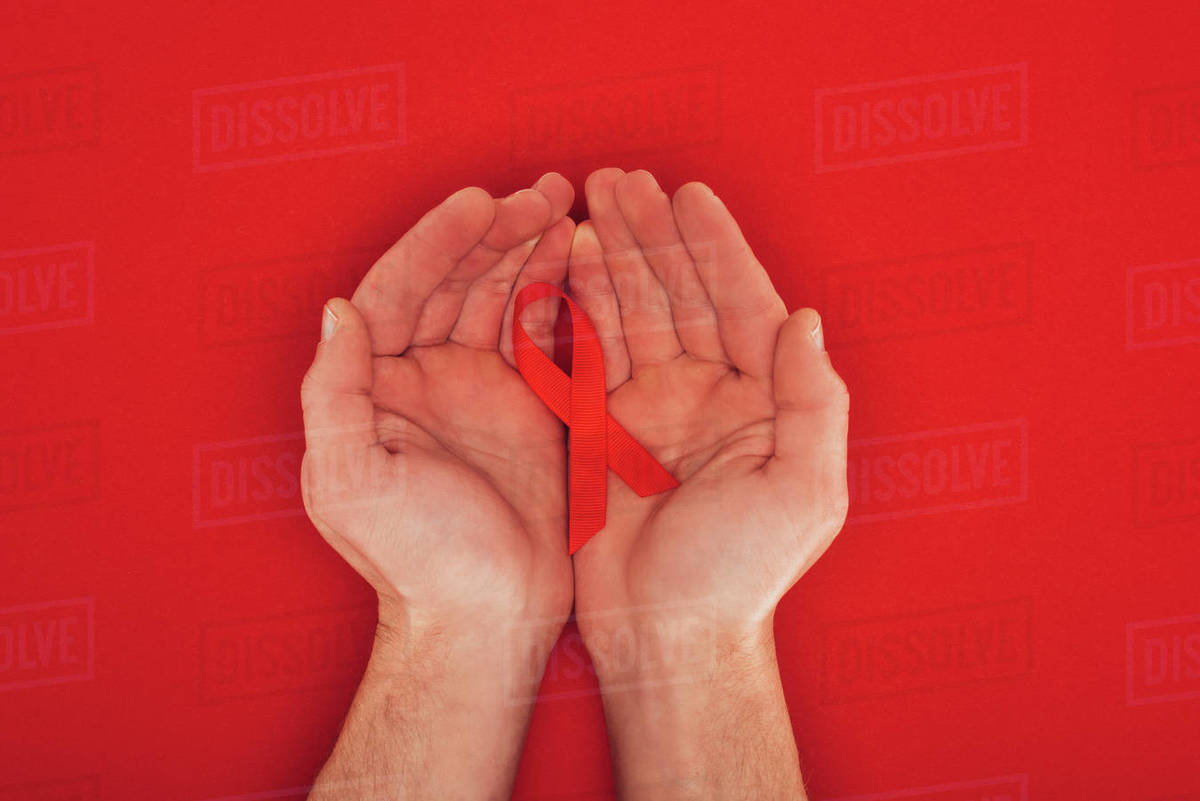 Cropped view of male hands with red aids ribbon, isolated on red ...