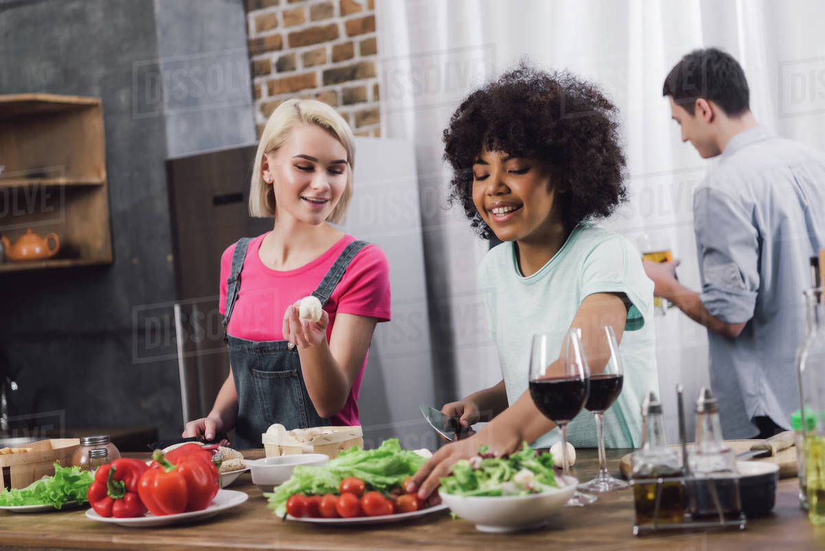 Smiling multiethnic girls cooking in kitchen - Royalty-free Stock Photo ...