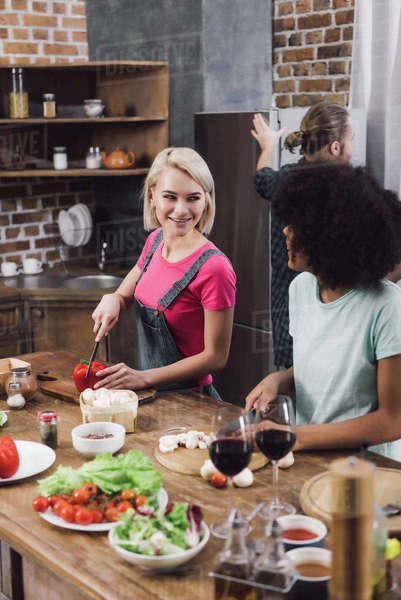 Smiling multiethnic girls cooking in kitchen - Stock Photo - Dissolve