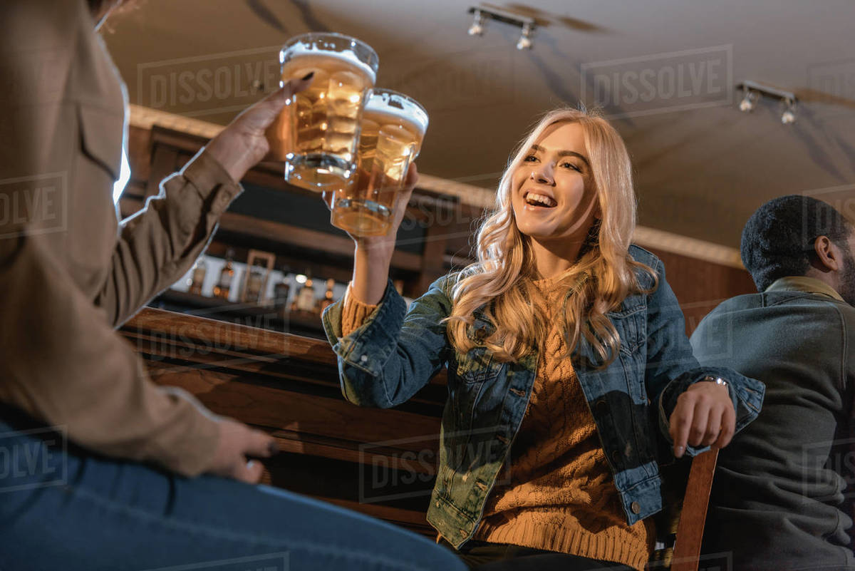 Two young women drinking beer at bar - Stock Photo - Dissolve