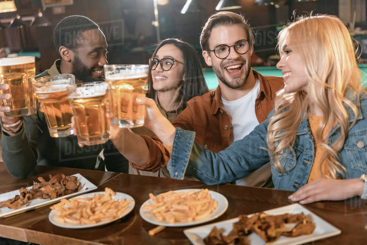 Young multicultural company eating and drinking at bar - Stock Photo ...