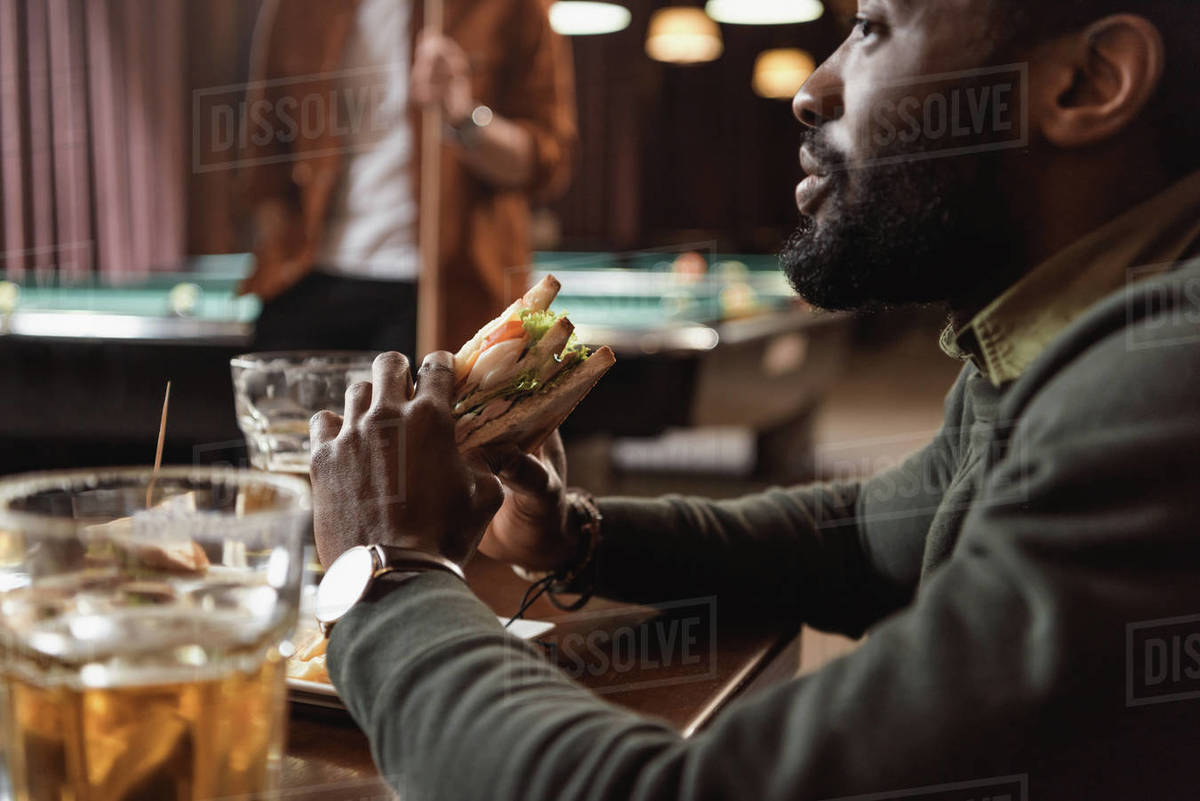 african amercian man eating sandwich at bar - Royalty-free Stock Photo ...