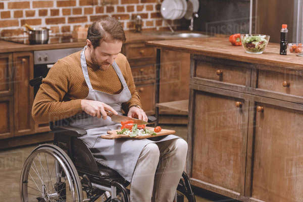 high angle view of disabled man in wheelchair cutting vegetables at ...