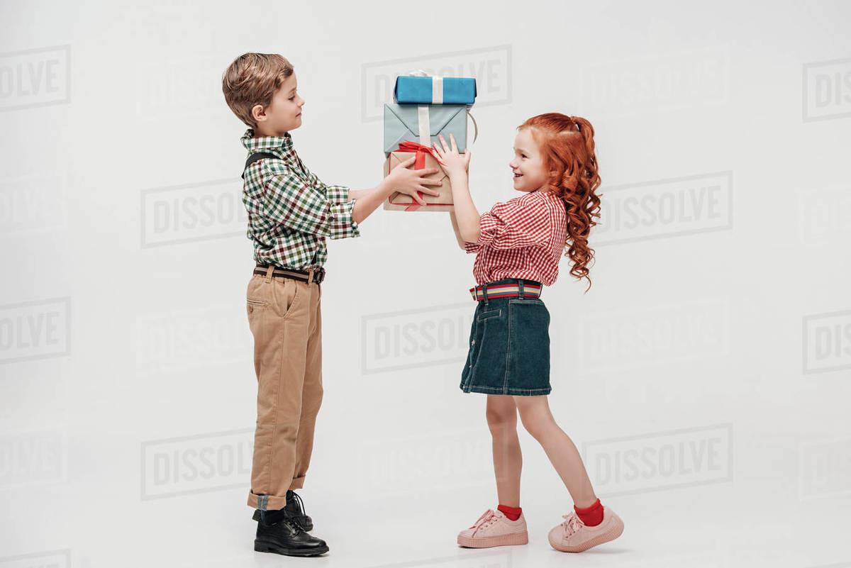 side view of beautiful smiling children holding presents isolated on ...