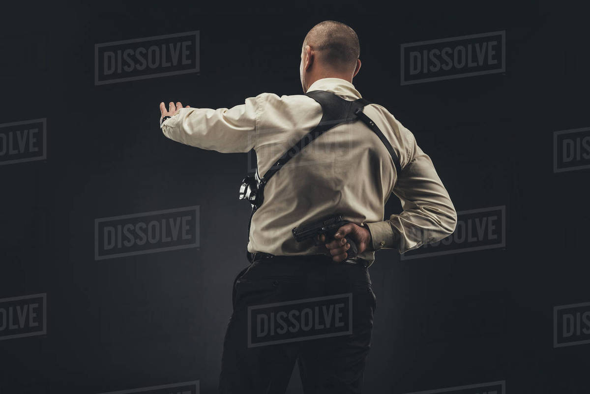 Security man showing stop sign and holding gun behind back - Royalty ...