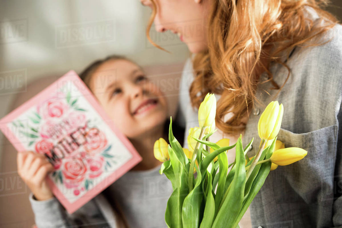 Selective focus of mother and daughter holding yellow tulips and happy ...