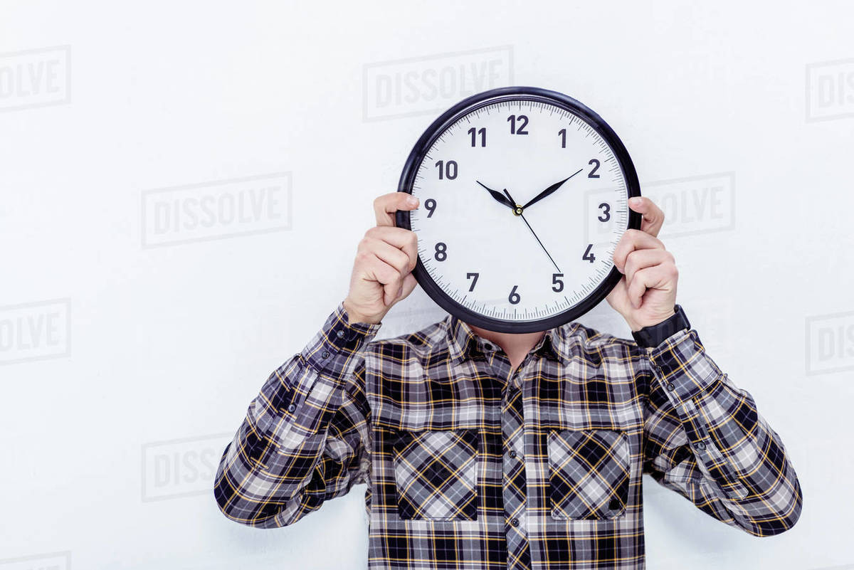 Man holding clock over face isolated on white - Stock Photo - Dissolve