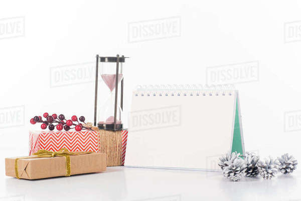 Close up view of blank calendar, sand clock, pine cones and wrapped ...