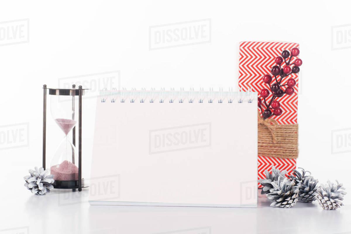 Close up view of blank calendar, sand clock, pine cones and wrapped ...