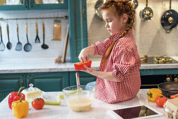 Adorable little child cooking while sitting on kitchen table - Stock ...