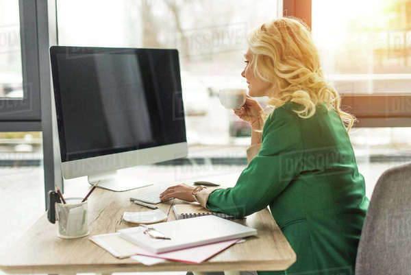 Middle aged businesswoman using desktop computer with blank screen and ...