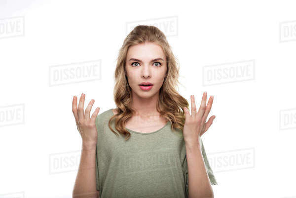 Attractive shocked woman standing and looking at camera isolated on ...