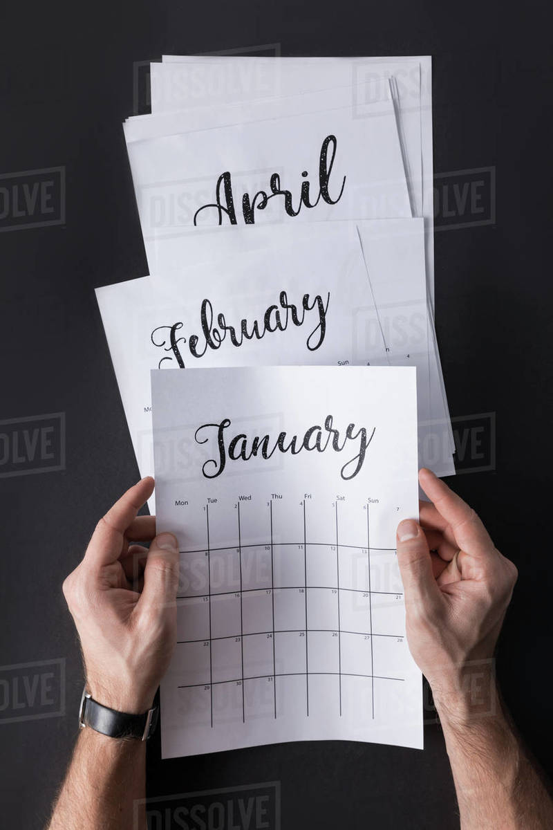Partial view of man holding calendar in hands isolated on black ...