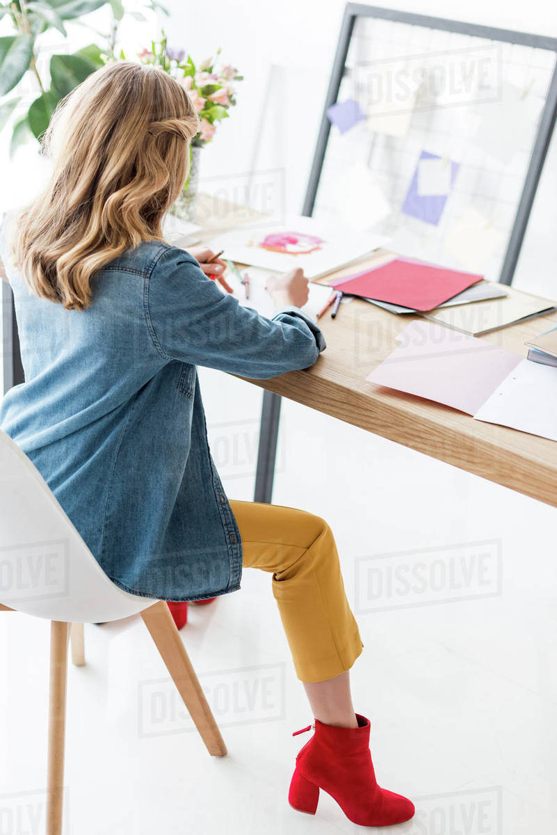 Rear view of magazine editor drawing sketches in modern office ...