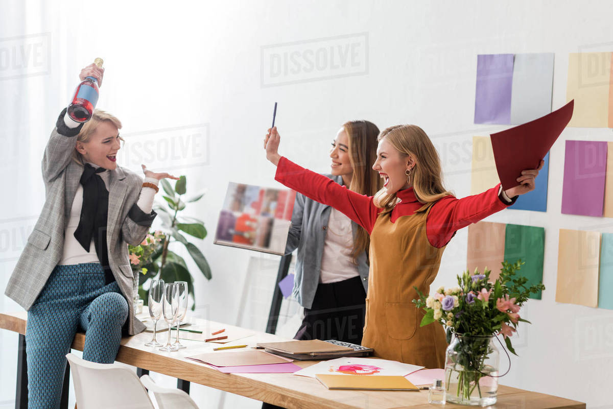 Excited magazine editors screaming and celebrating with champagne in ...