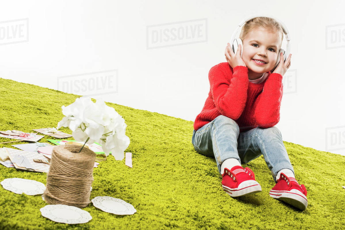 Adorable little child listening music with headphones while sitting on ...