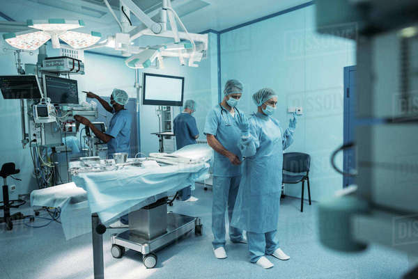 Doctor helping to wear surgical uniform in operating room - Stock Photo ...